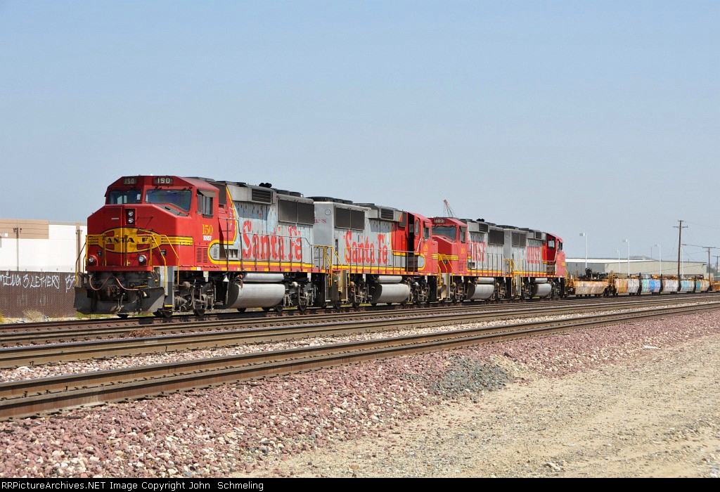 BNSF 150 (ex ATSF GP60M 150) leads a lashup of red and silver GP60M's on an empty intermodal ...